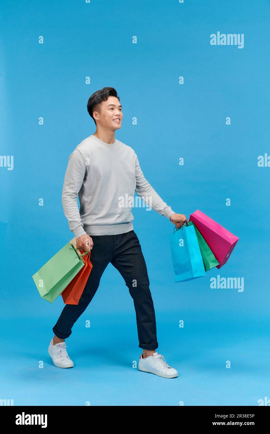 man happy positive smile go walk step shopping bags isolated over blue ...