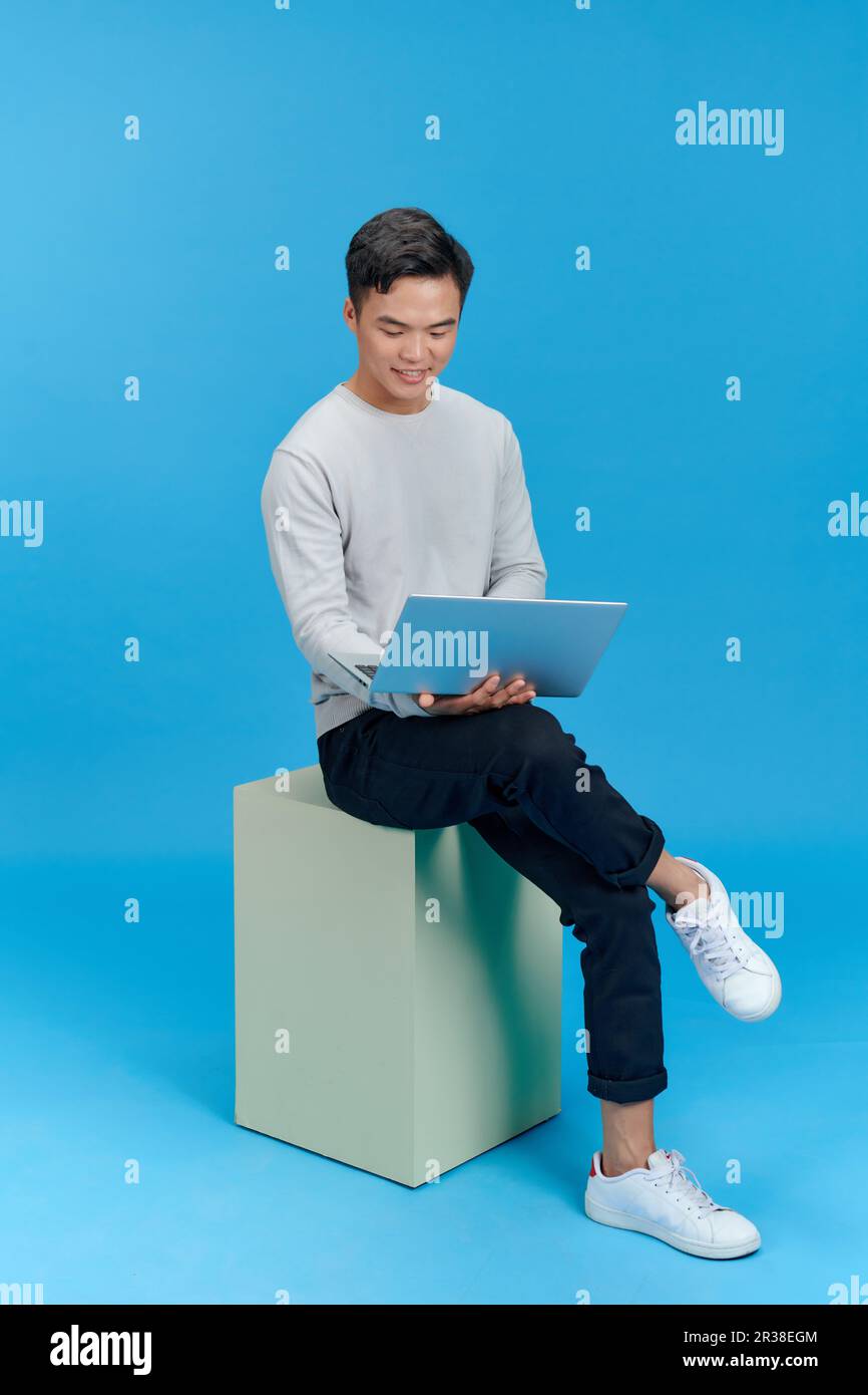 man sitting on a white cube with a laptop computer Stock Photo - Alamy