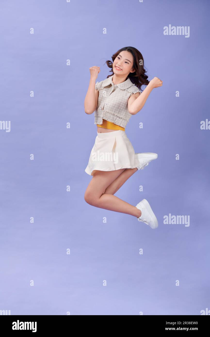 Full length of cheerful young woman jumping high smiling showing power ...
