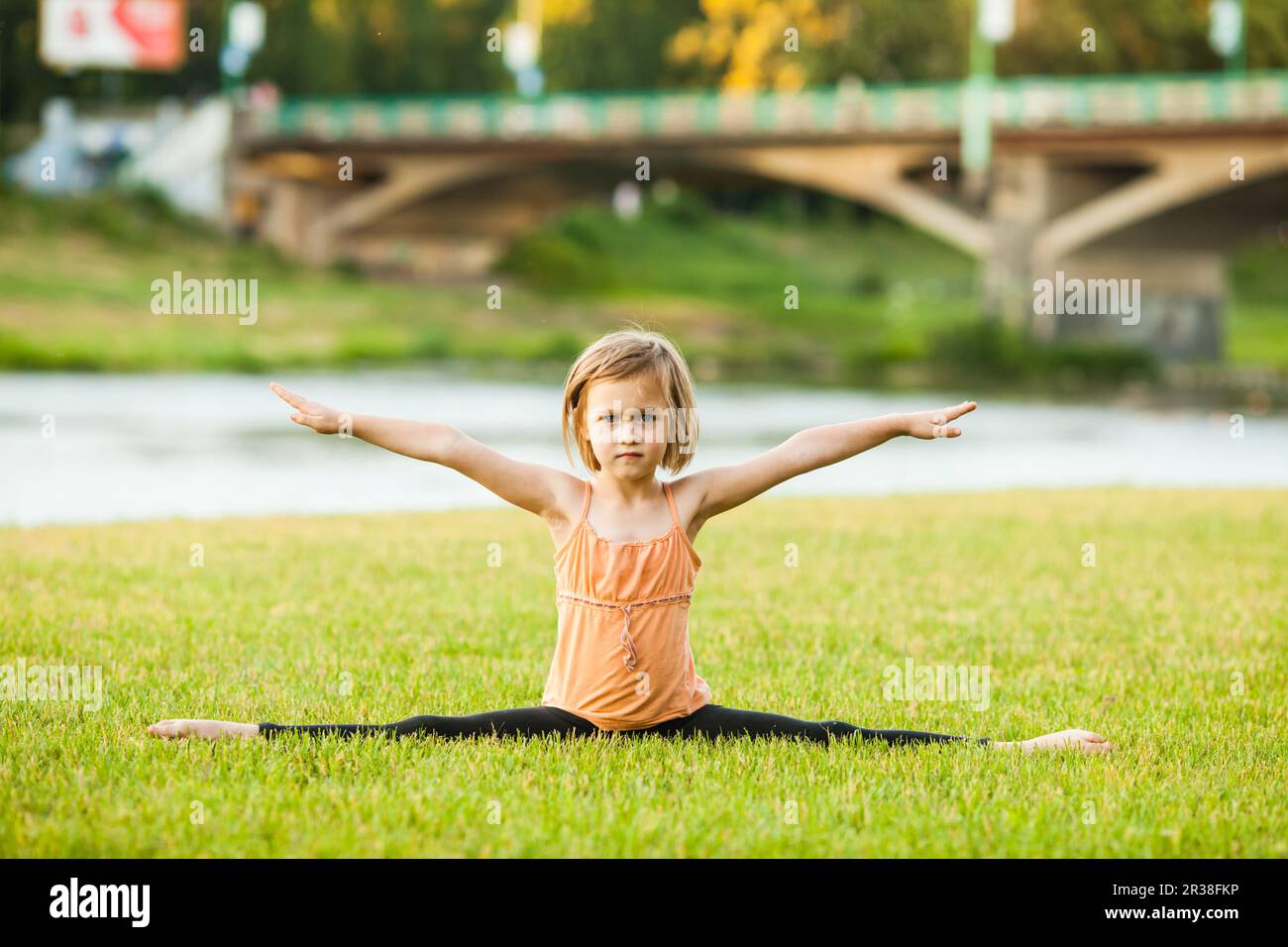 Young girl sitting in the split pose on the grass Stock Photo - Alamy