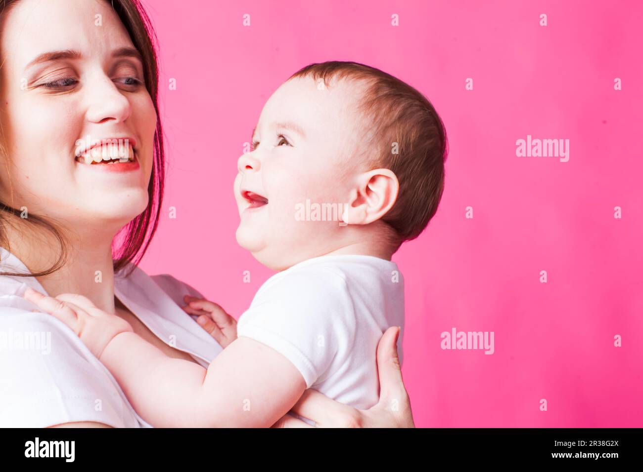 Happy mother looking at her smiling child, on a pink background Stock ...
