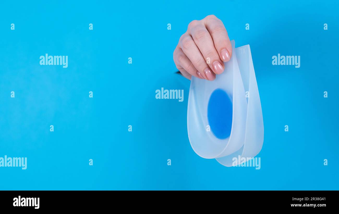 Woman holding orthopedic silicone heel pads. A woman's hand sticks out ...