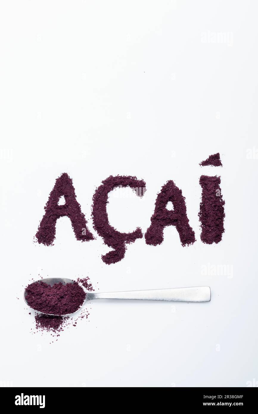 Acai berry powder: on a spoon and lettered against a white background ...
