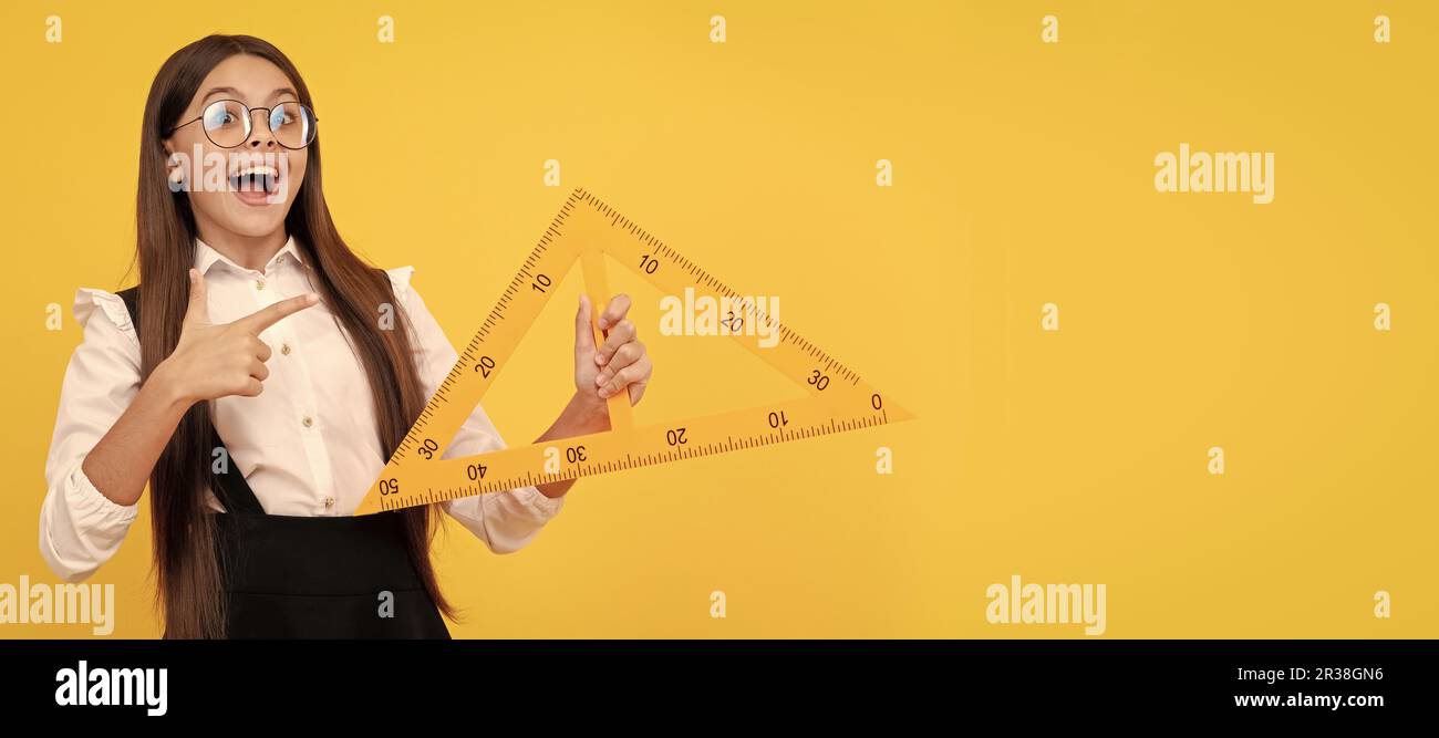 amazed child in school uniform and glasses hold mathematics triangle ...