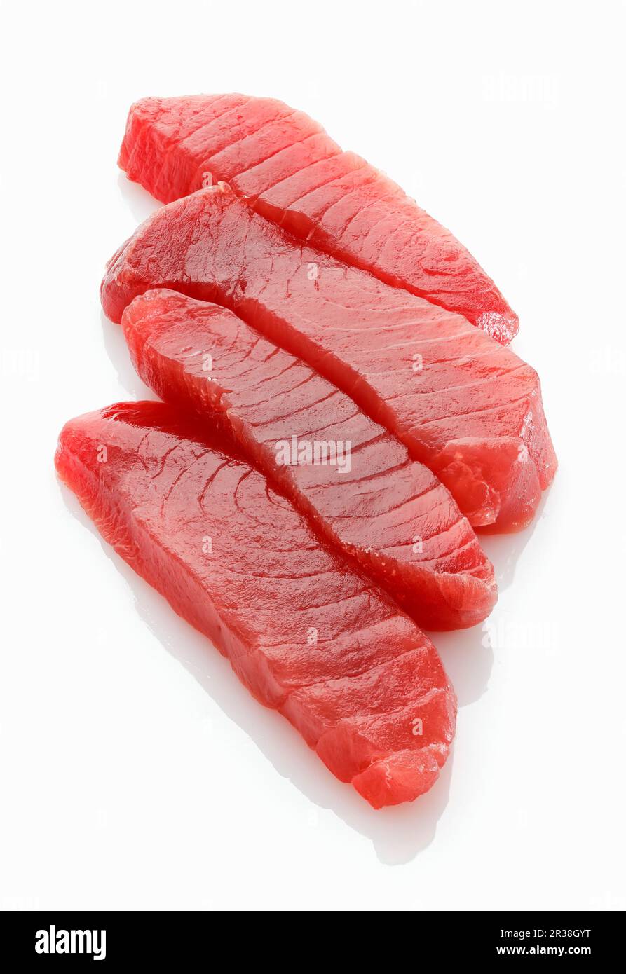 Four fresh tuna fish steaks on a white surface Stock Photo - Alamy