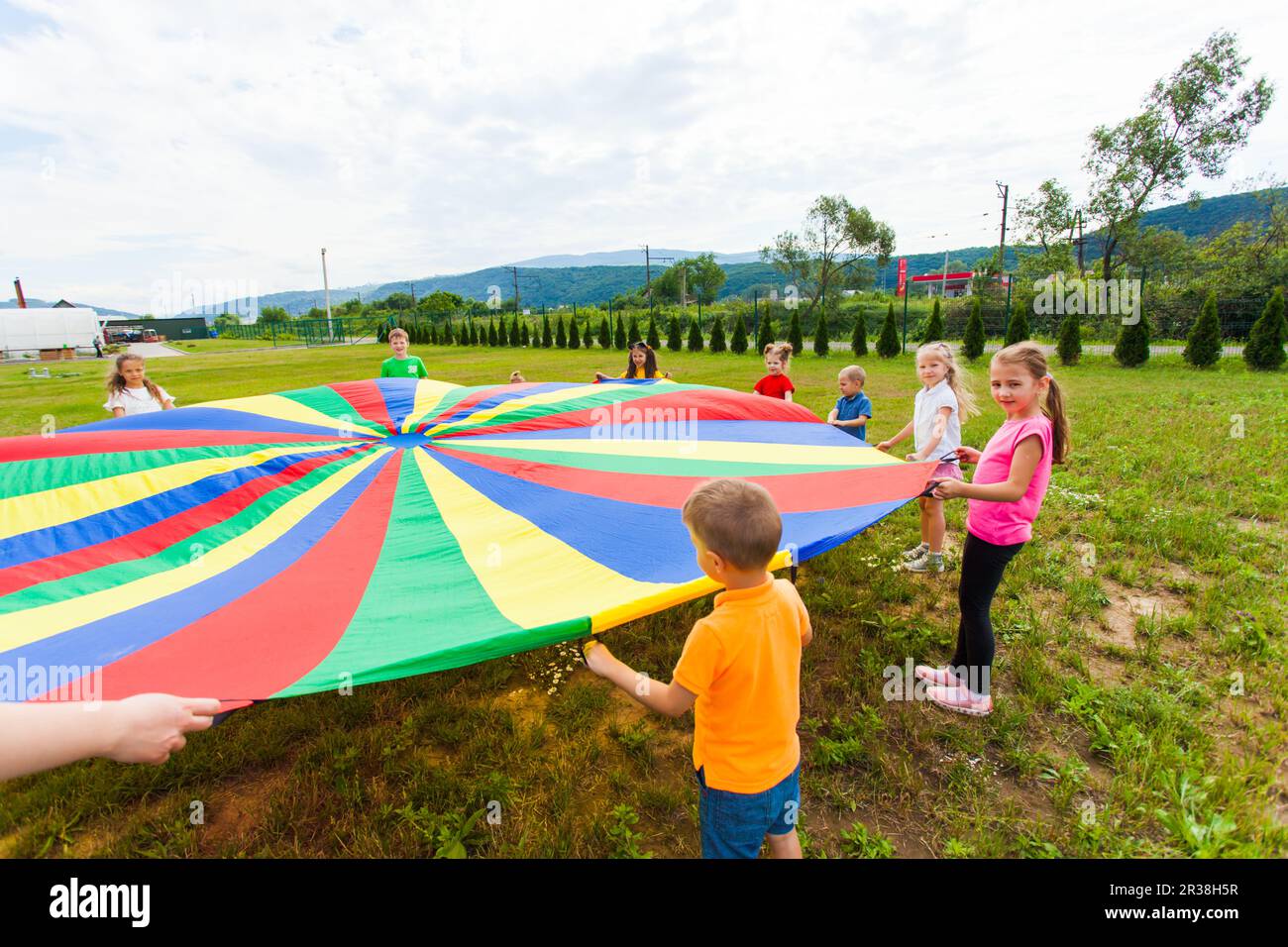 Happy kids spreading colourful parachute Stock Photo - Alamy