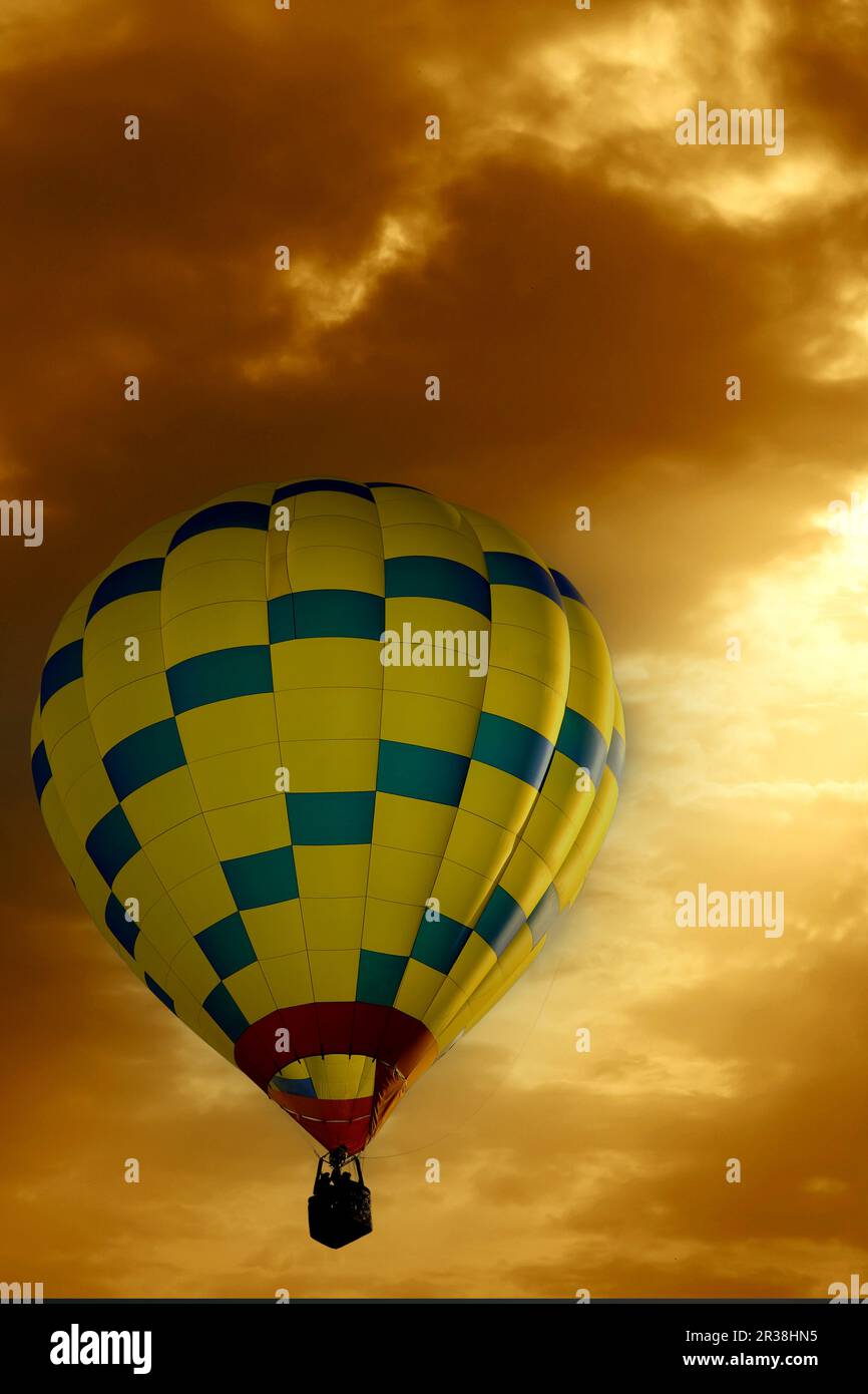 Hot air balloon in flight in an early morning cloudy sky, with sunlight ...