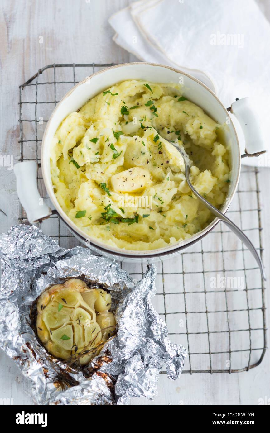 Homemade mashed potatoes with butter in a pot and baked garlic in ...