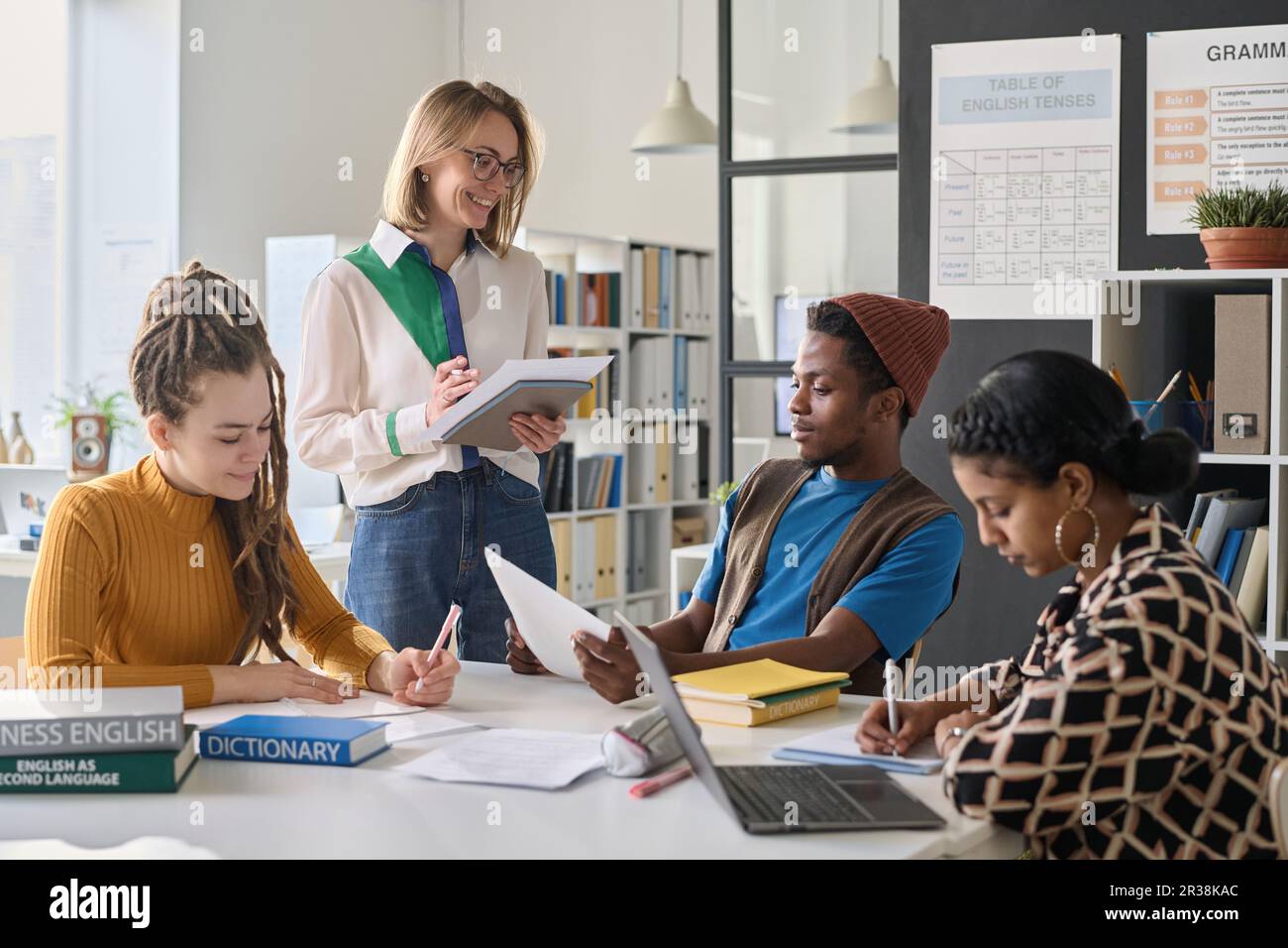 Young smiling teacher conducting foreign language lesson with students ...