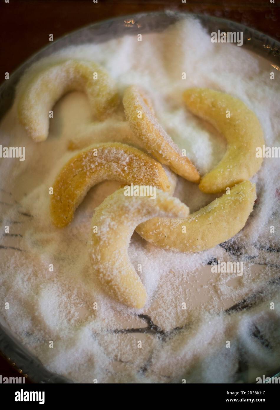 Baked vanilla crescent biscuits being rolled in sugar Stock Photo - Alamy