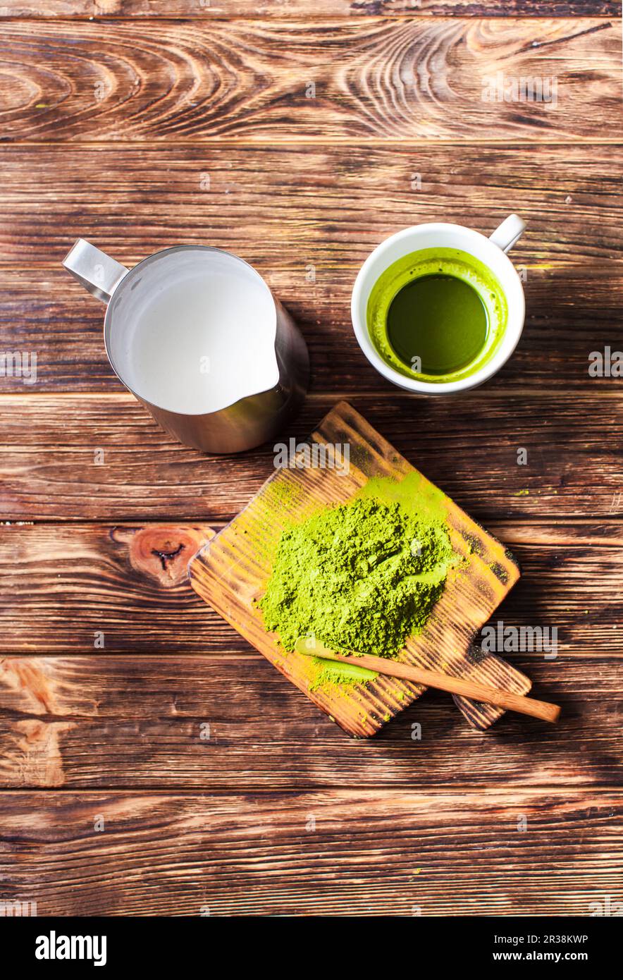 Matcha tea with powdered green tea and milk jug on a dark rustic wooden ...