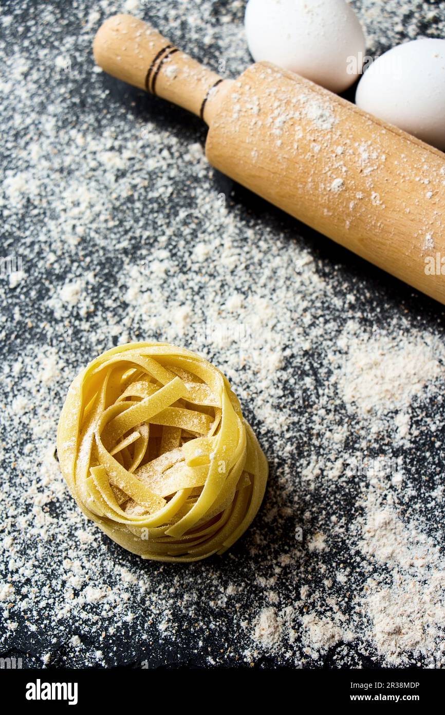 Ribbon pasta with a rolling pin on a floured work surface (top view ...