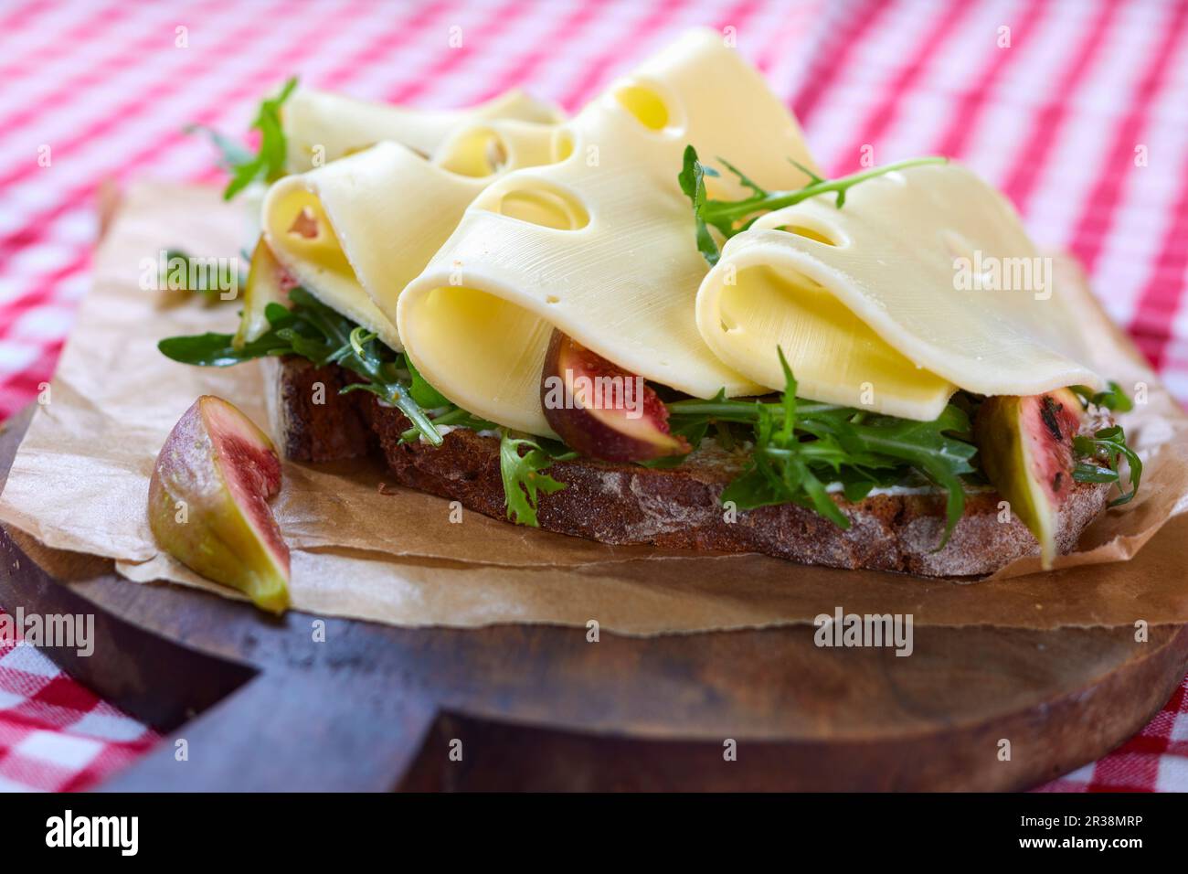 A slice of crusty bread topped with gouda, figs and rocket Stock Photo ...