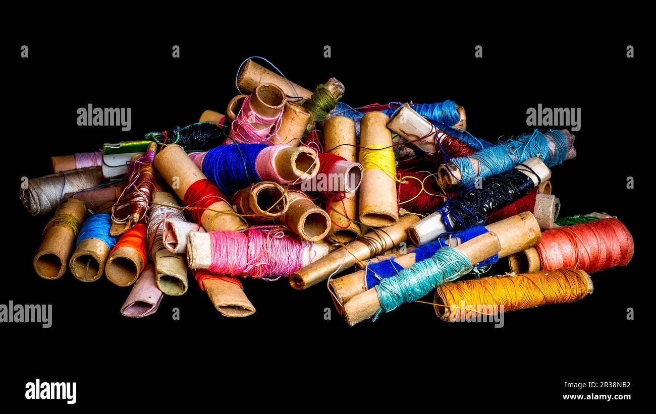 Pile of used colorful spools of thread tailoring, on black background ...