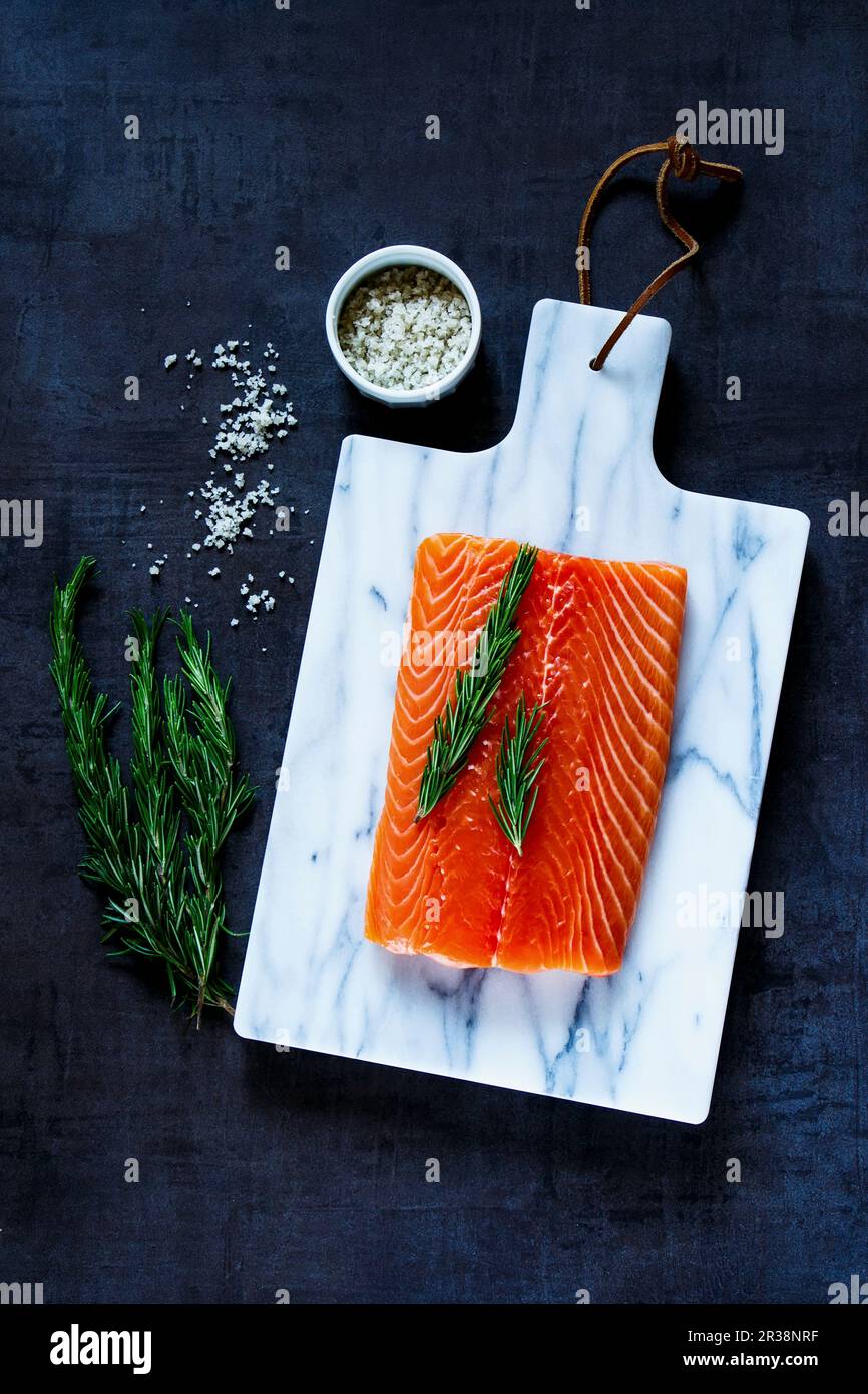 Fresh raw salmon fillet with rosemary and grey salt on marbre cutting ...