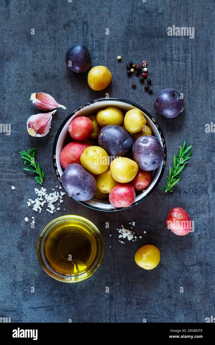 Cooking background with fresh potatoes, garlic and olive oil over dark ...