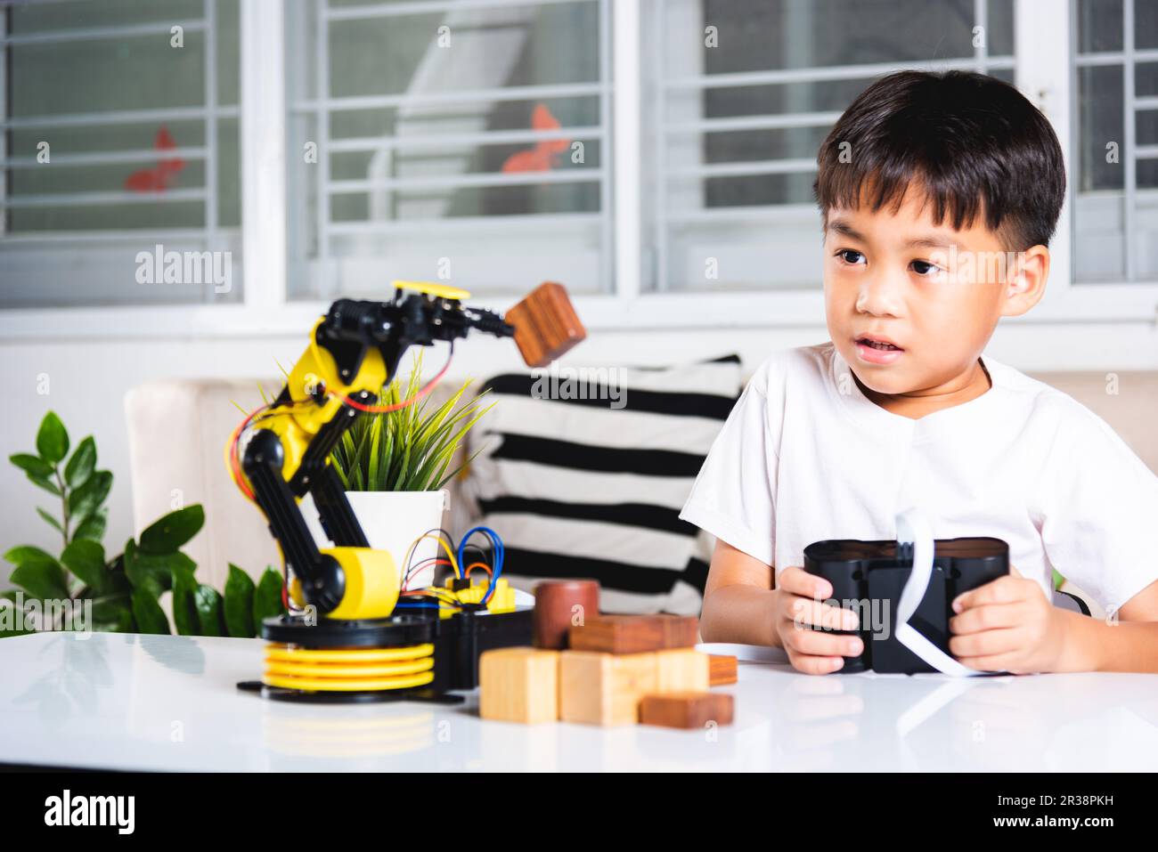 Happy Asian little kid boy using remote control playing robotic machine ...