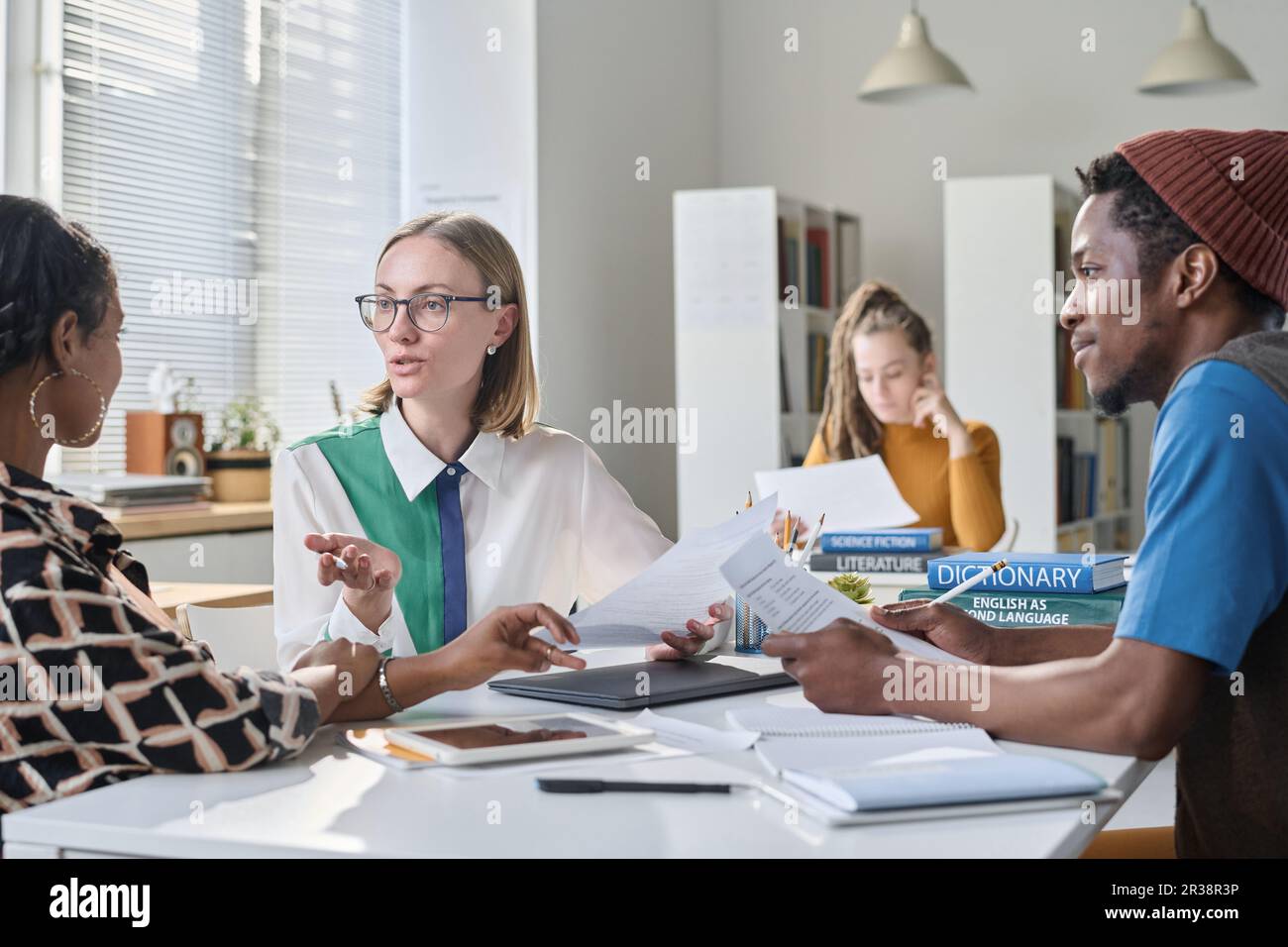 Young teacher teaching foreign language to students while they sitting ...