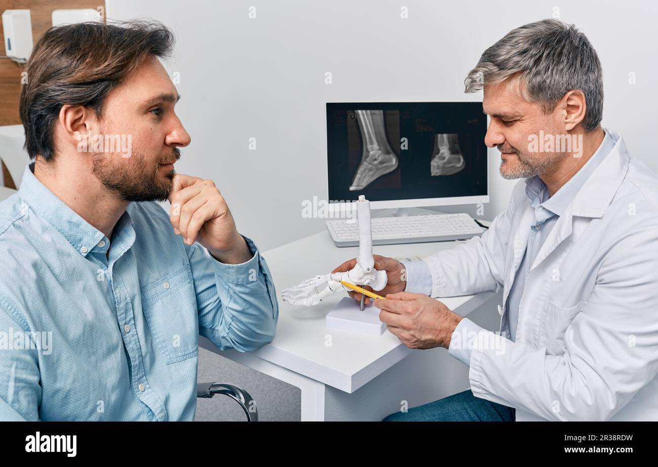 Orthopedic doctor consulting adult man with leg injury and explaining ...
