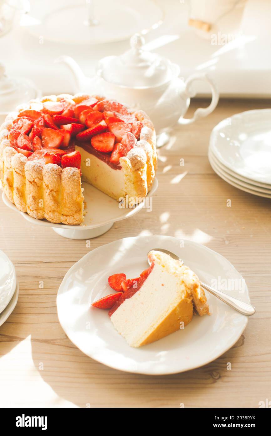 French Fresh Strawberry charlotte cake with teapot Stock Photo - Alamy