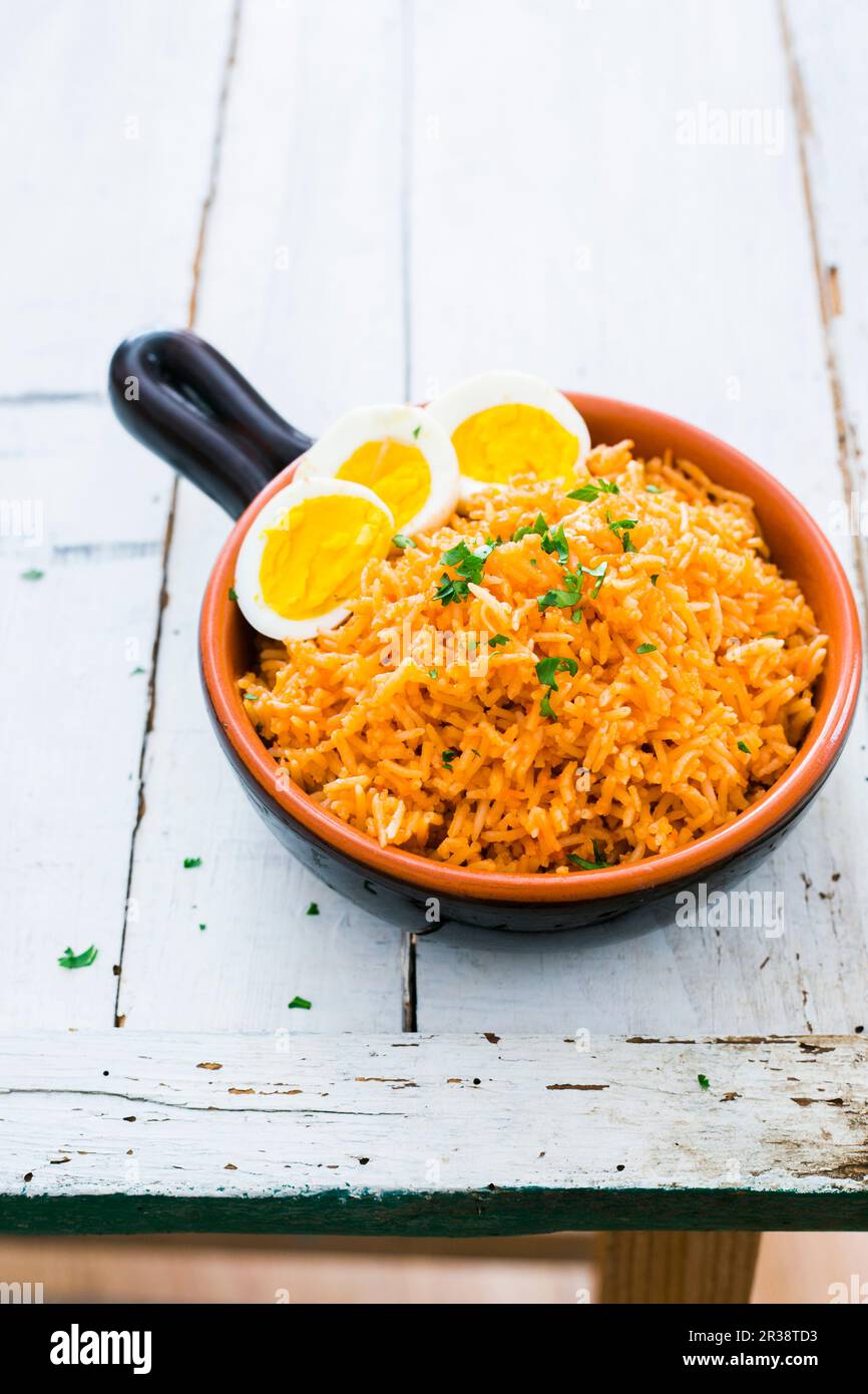 A terracotta bowl containing mexican red tomato rice garnished with ...