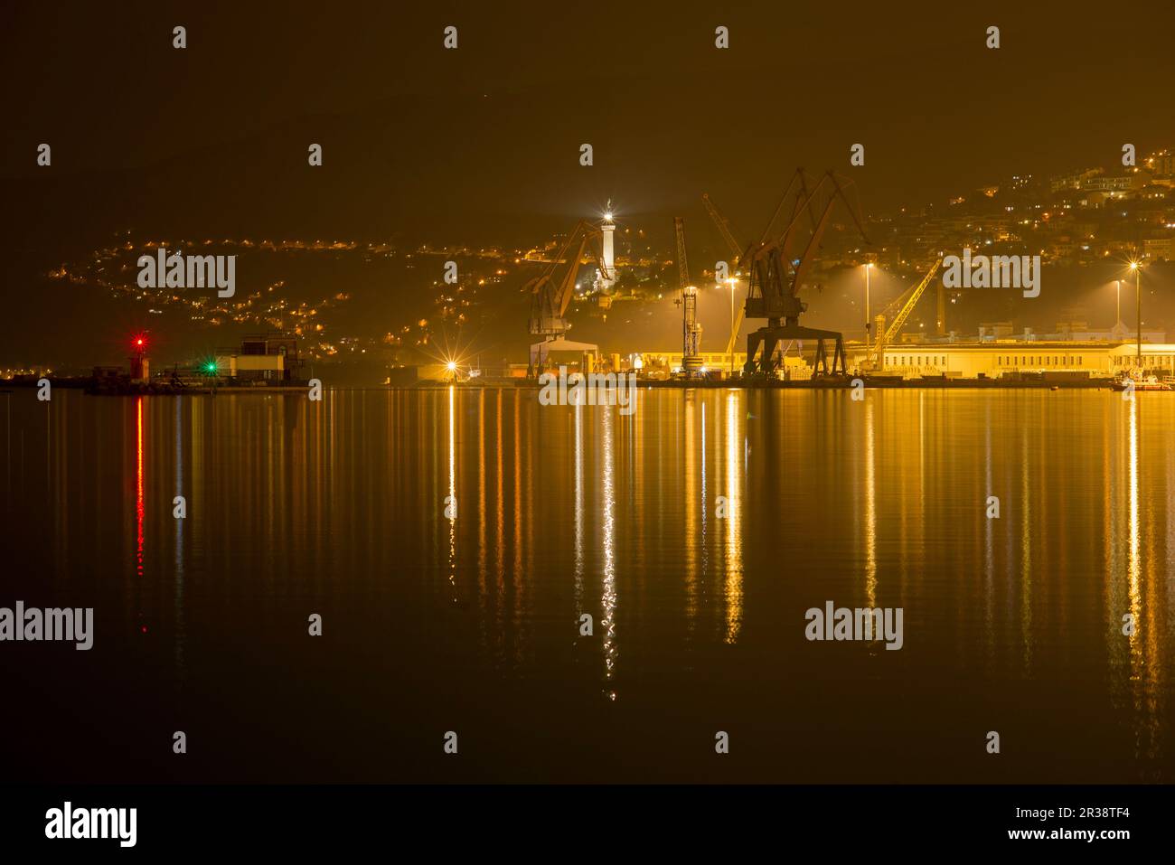 big port cranes and lighthouse by night in Trieste city, Italy Stock ...