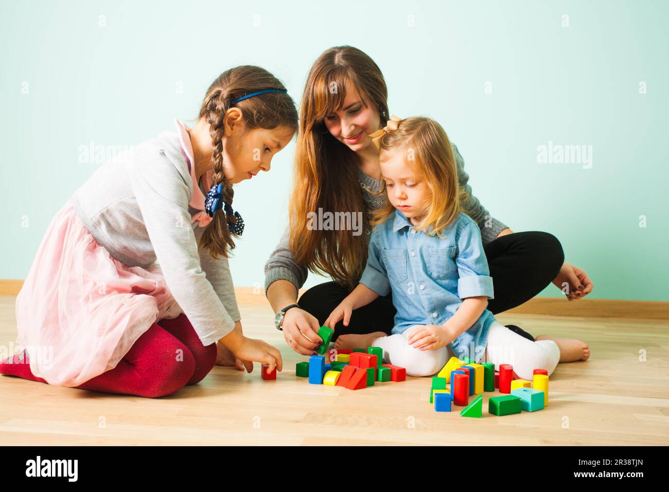 Young nanny playing with kids while babysitting Stock Photo - Alamy
