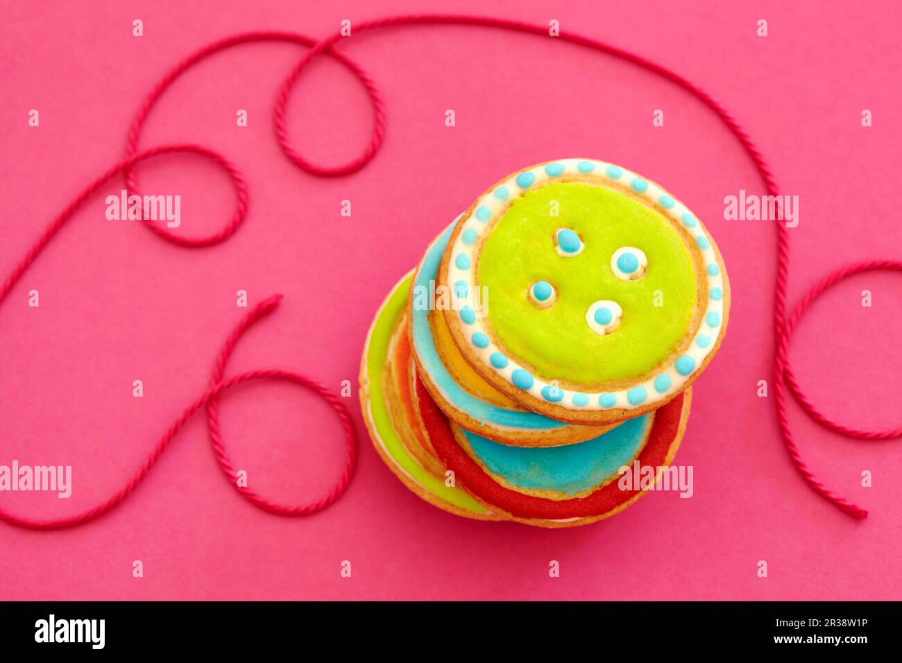 Button biscuits with colorful icing in front of a pink background Stock ...