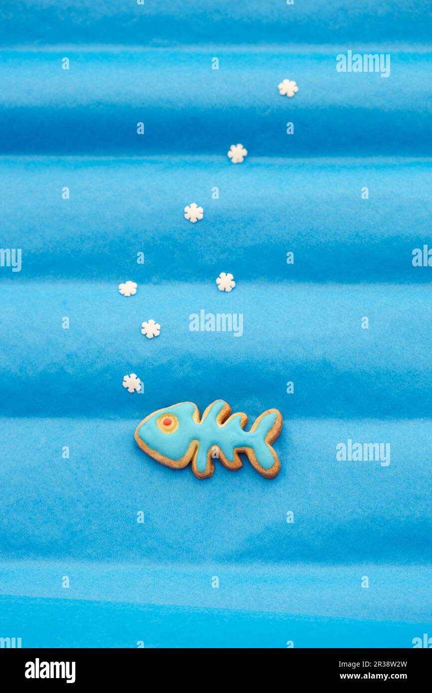 A fish shaped biscuit with blue icing against a blue background Stock ...