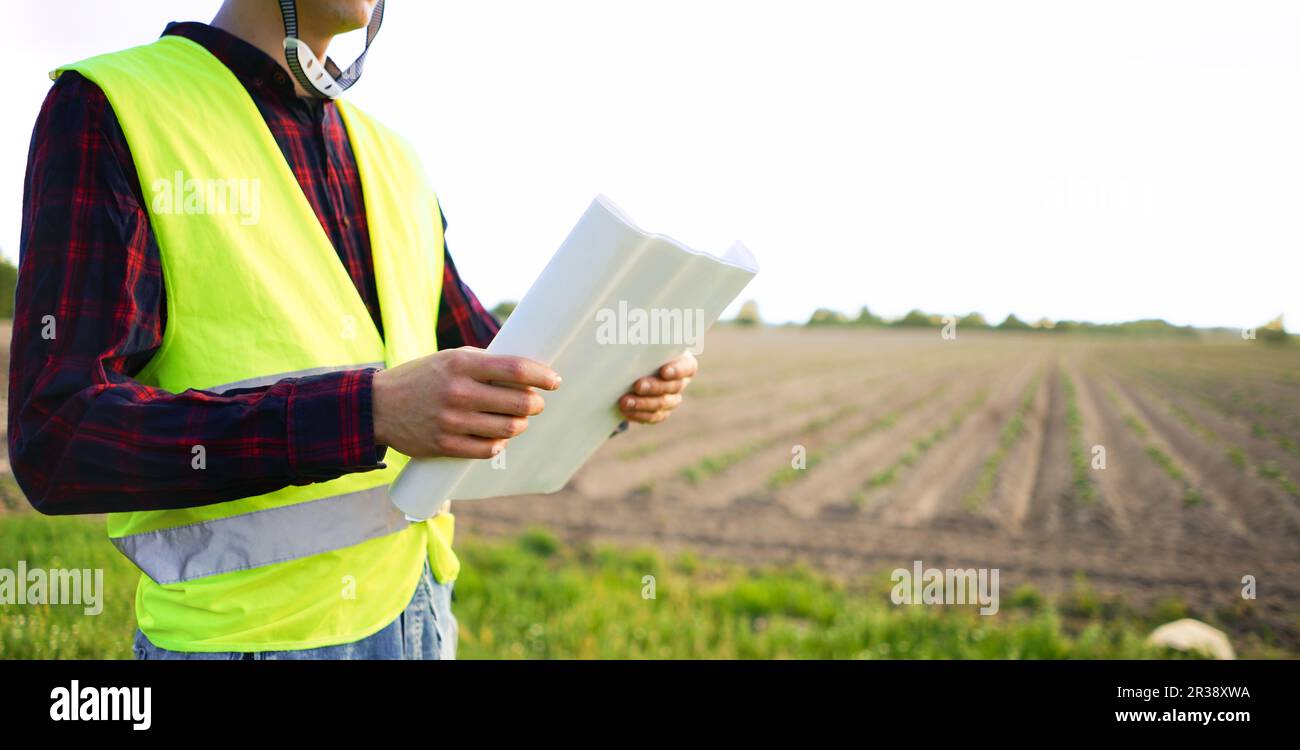 Construction worker holding plan construction plan. Empty field in the ...