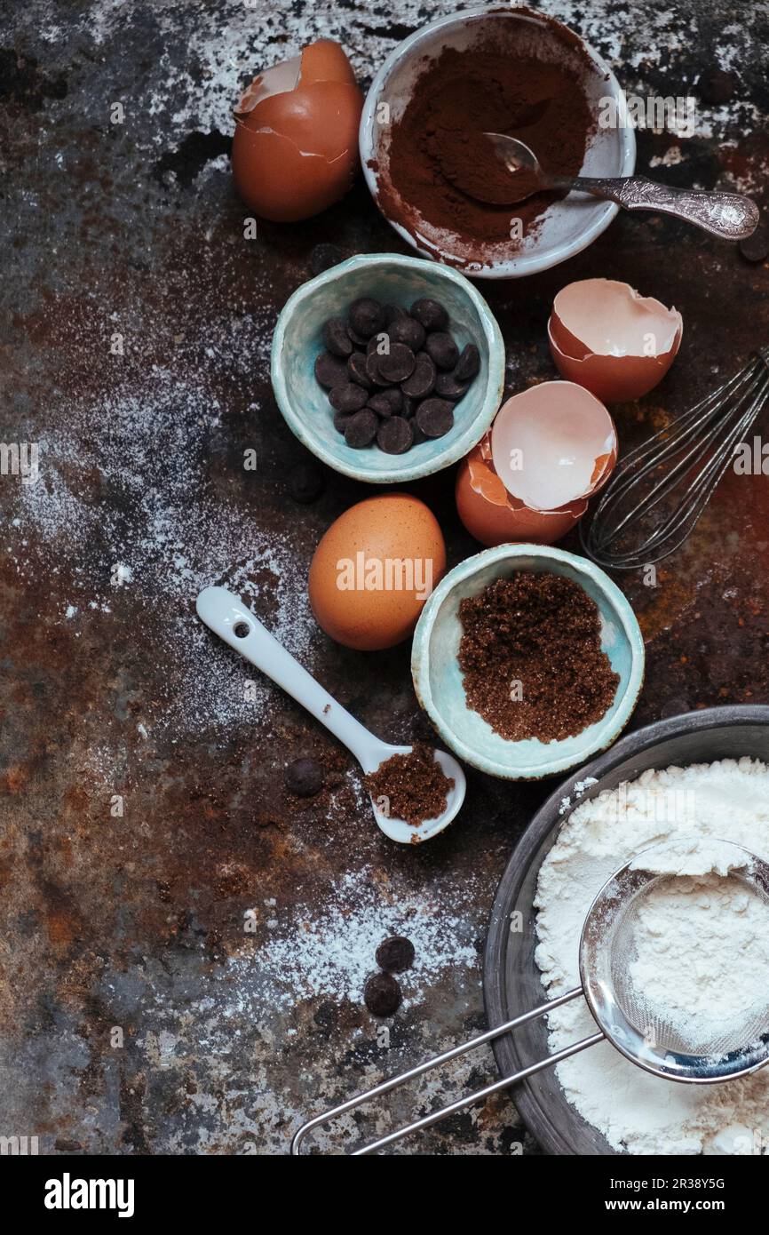 An arrangement of baking utensils: cocoa, chocolate chips, eggs, flour ...
