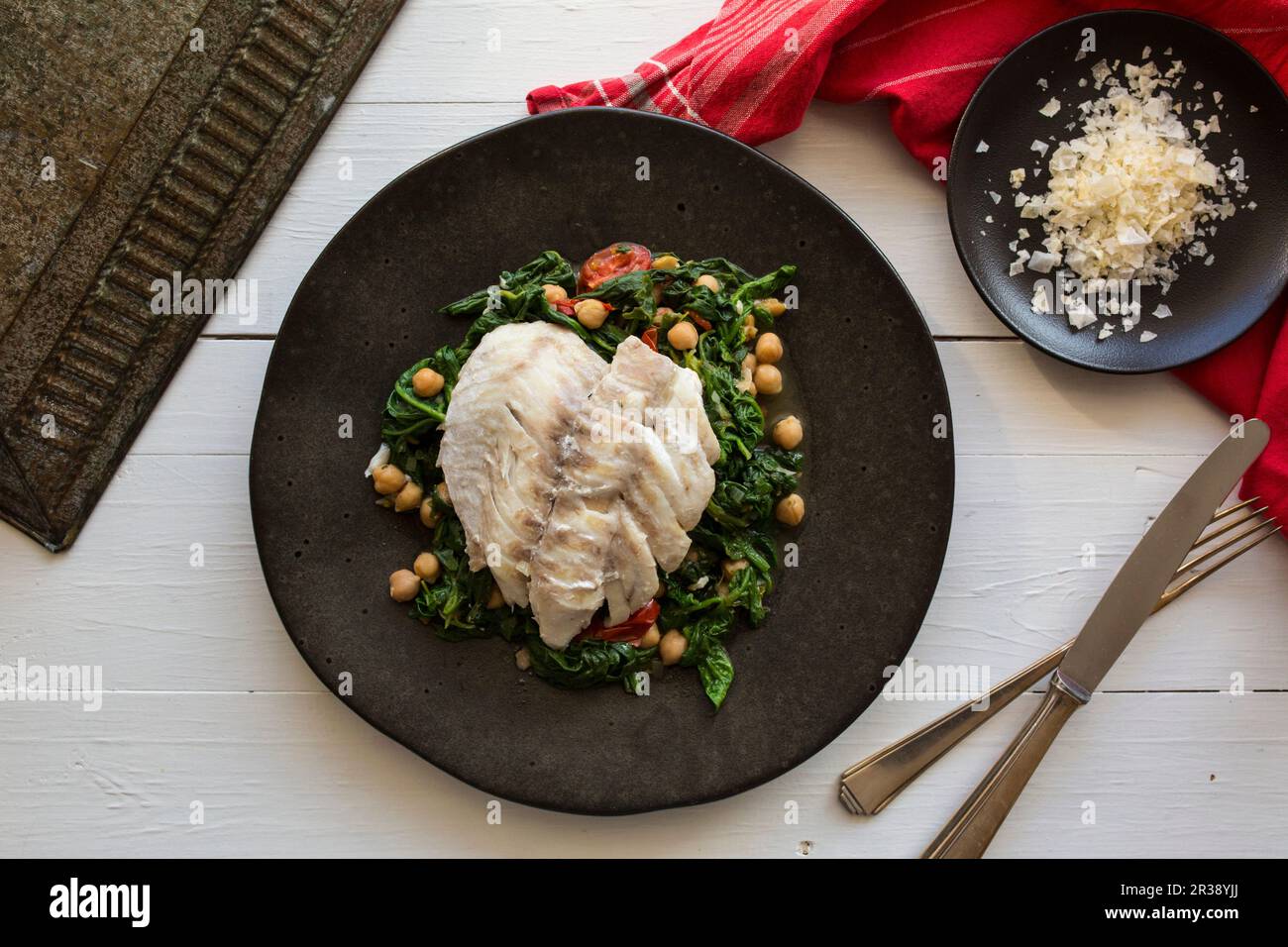 Rose fish on a bed of spinach with chickpeas, tomatoes and cumin Stock ...