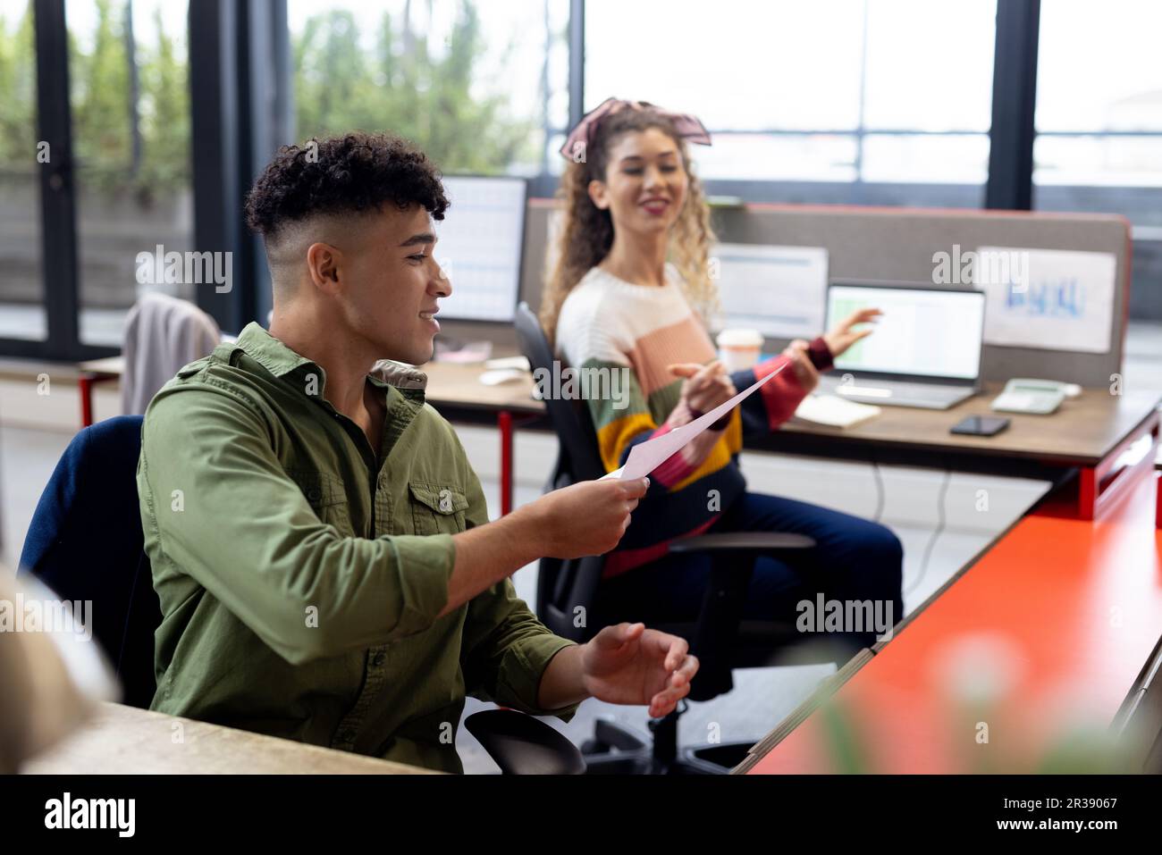 Happy diverse business people discussing work at desks in creative ...