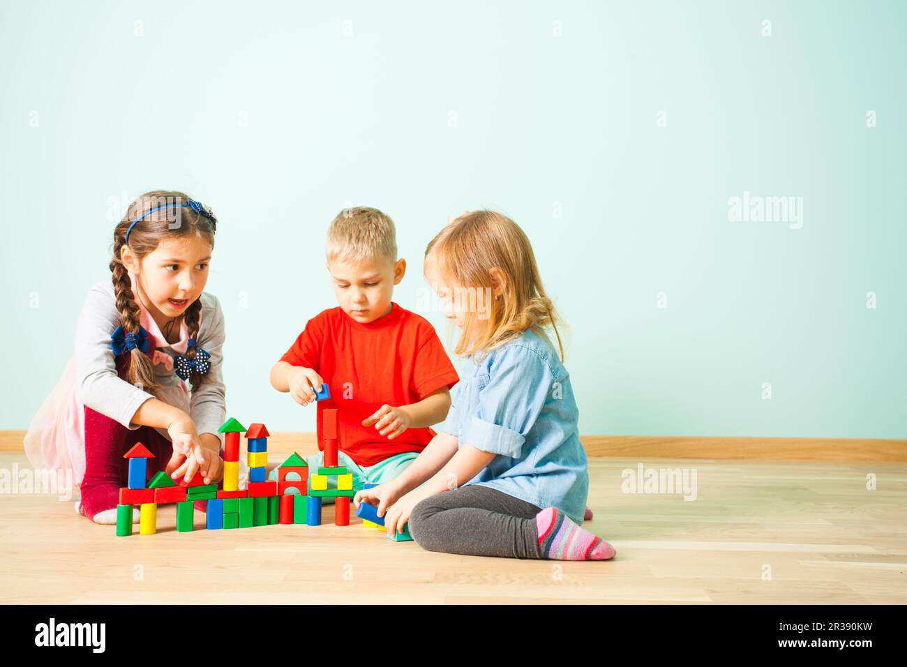 Young kids constructing towers from wooden blocks Stock Photo - Alamy