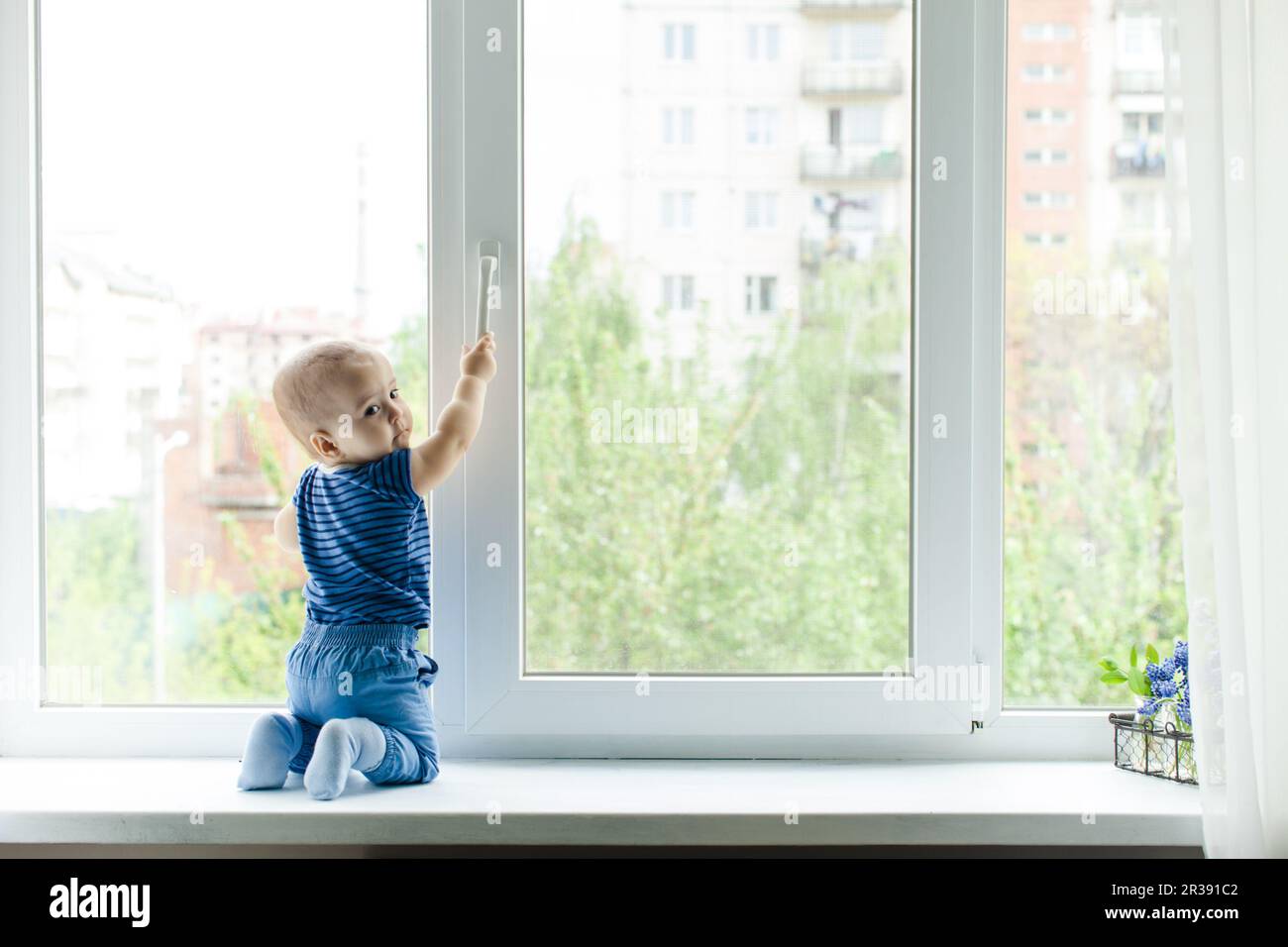 Little boy on the windowsill, danger in the home Stock Photo - Alamy