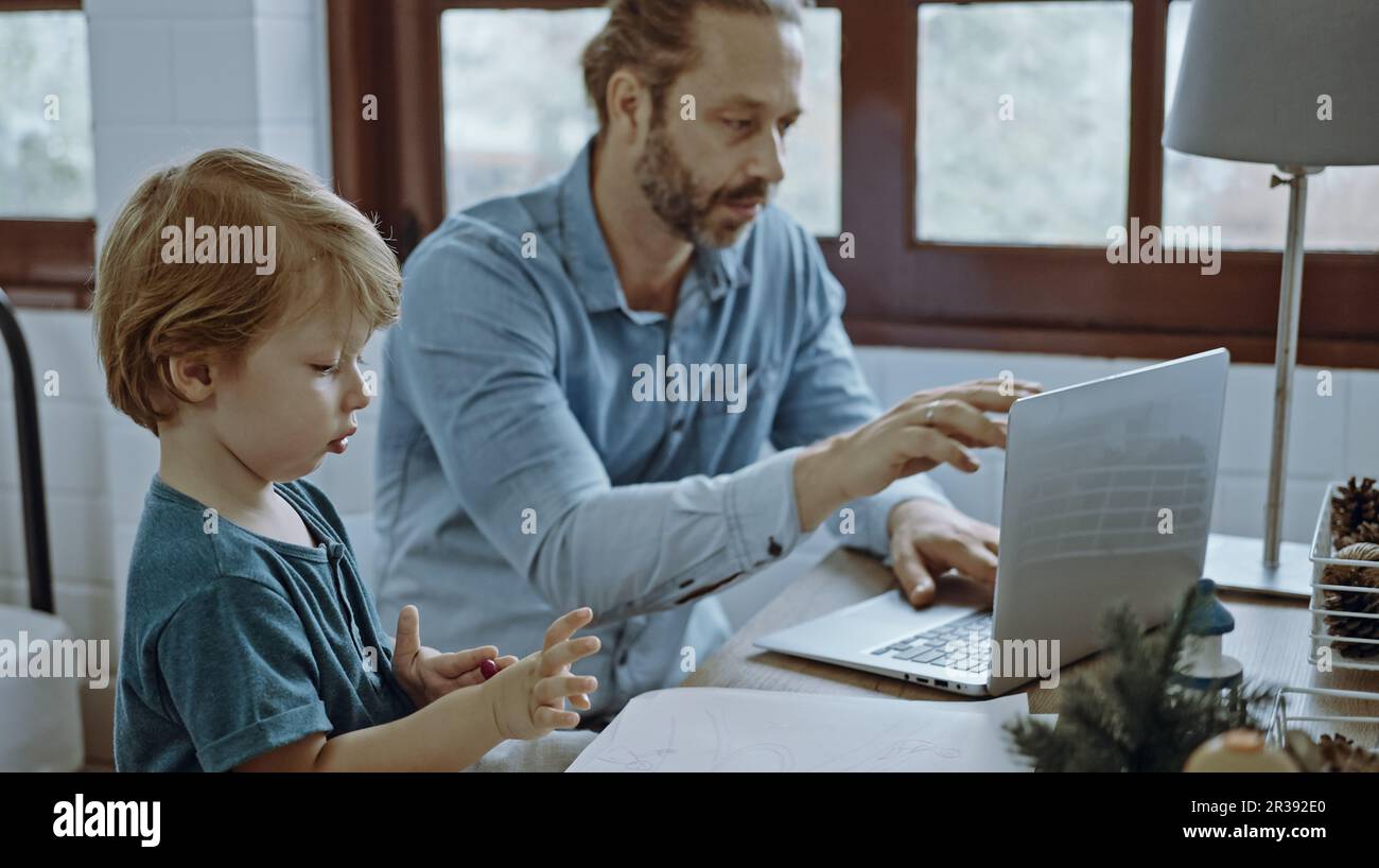 Father working from home office using laptop sit at table with cute ...
