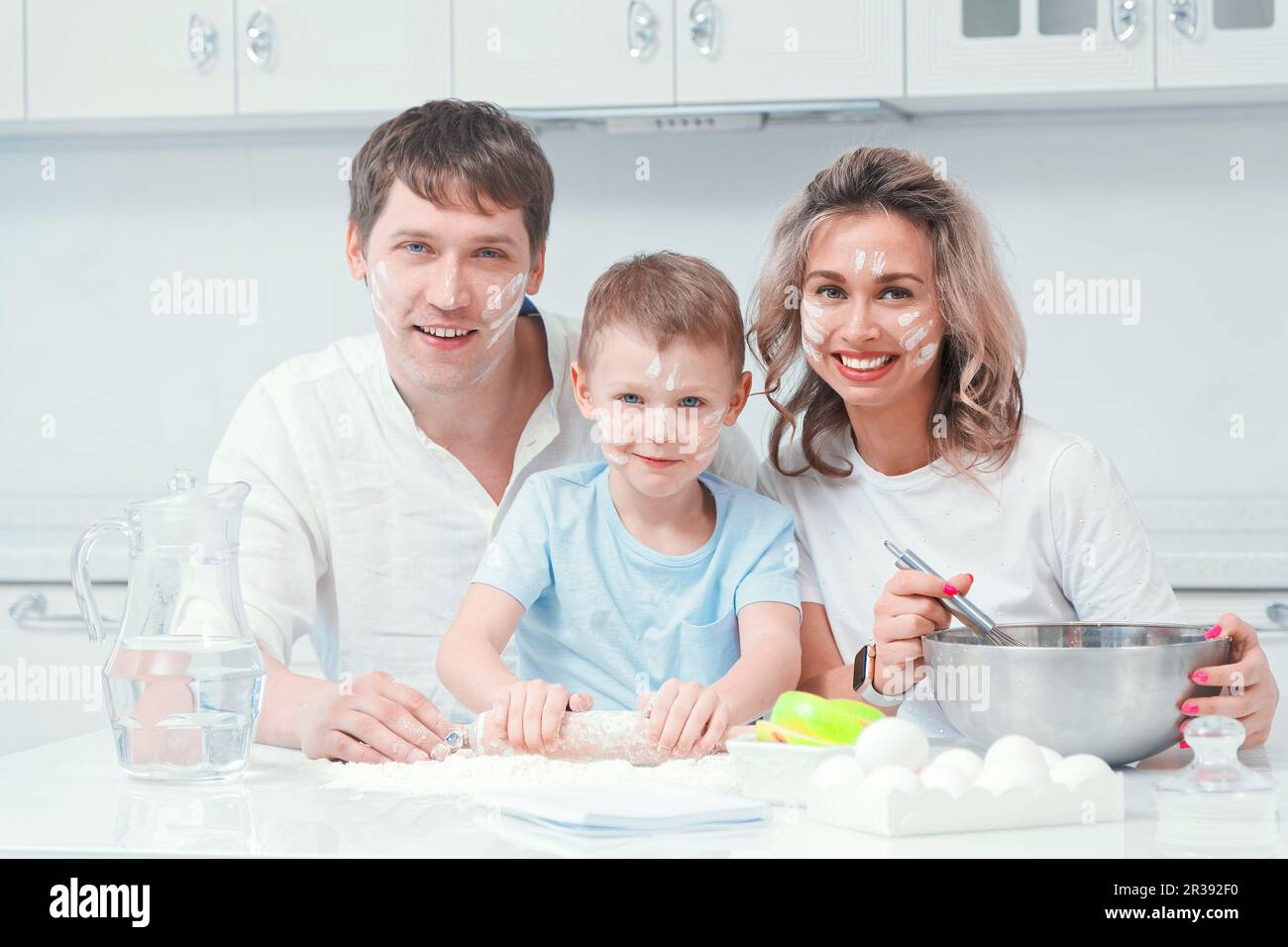 Beautiful caucasian family of three is sitting at home cooking table ...