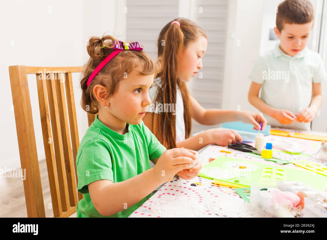Little girl makes handicraft in front of other children Stock Photo - Alamy