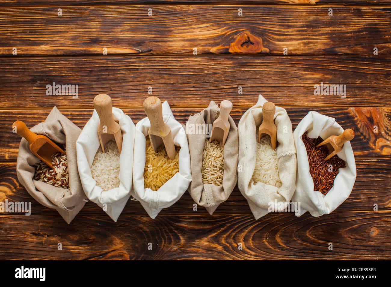 Different rice types in textile bags on wooden background Stock Photo ...