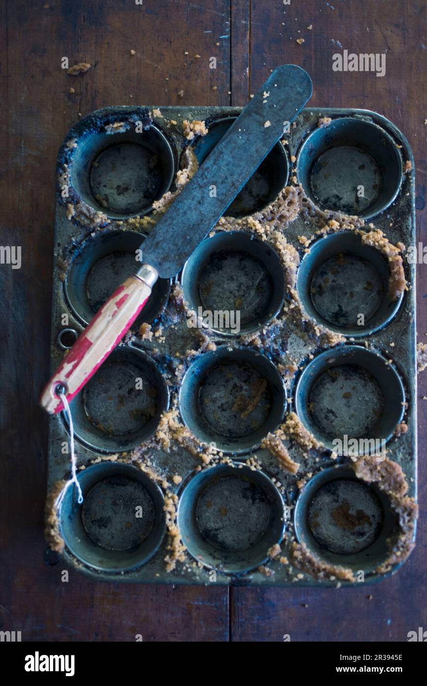 An empty muffin tins with cake crumbs and a palette knife Stock Photo ...