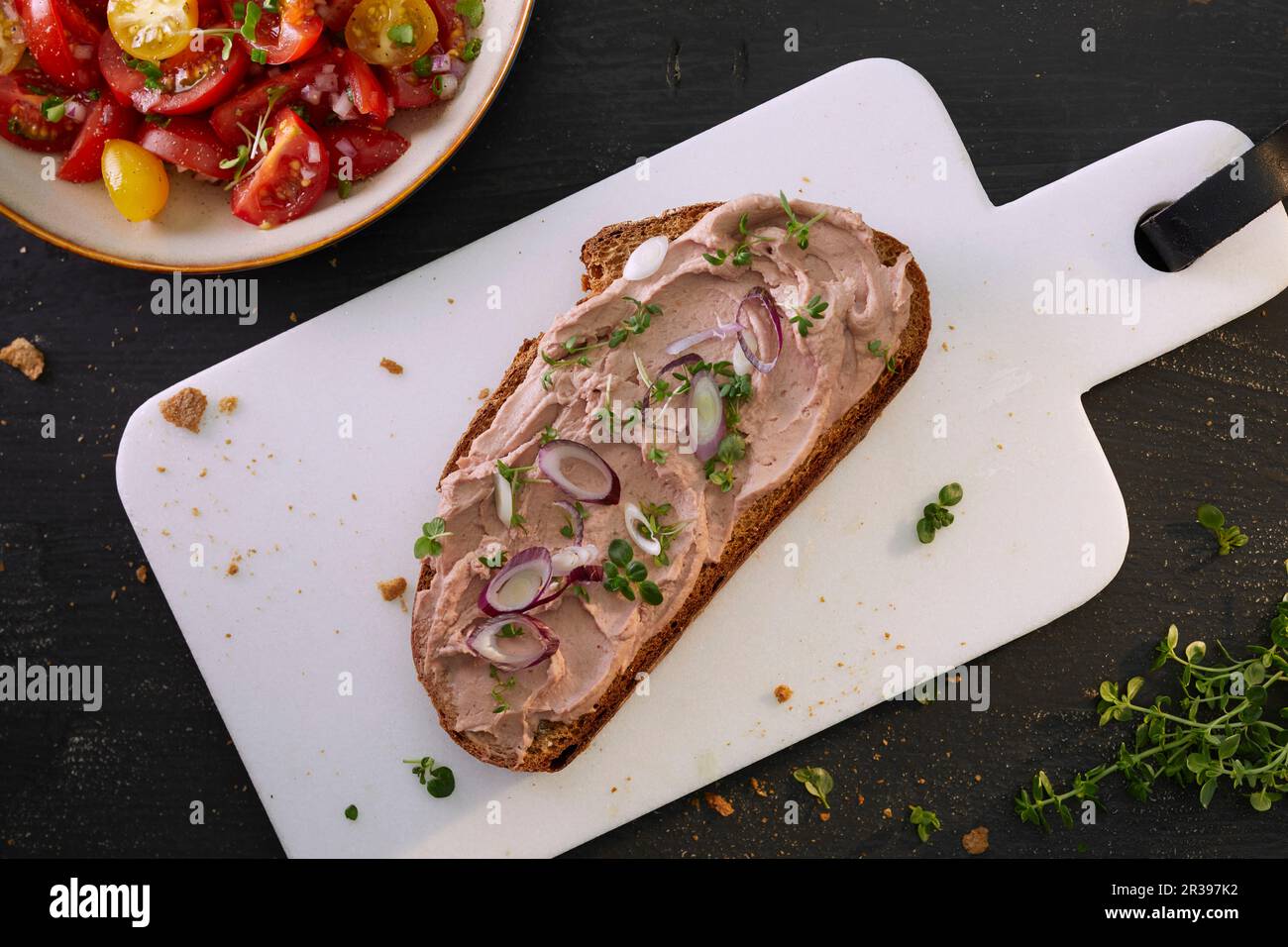 A slice of bread spread with liver pâté and spring onions served with ...