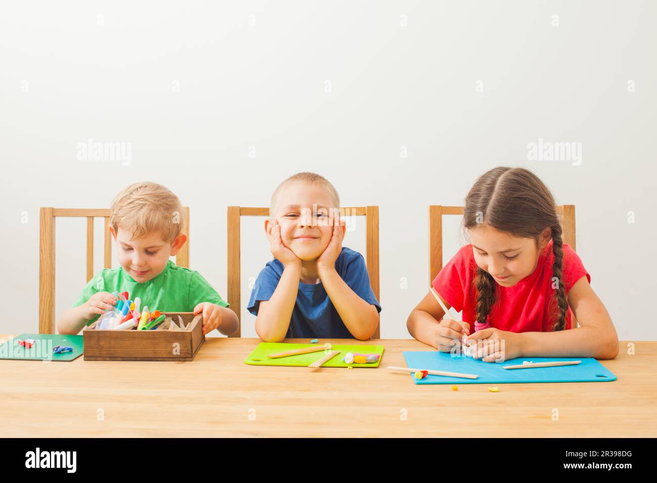 Different age children having fun together with colorful modeling clay ...