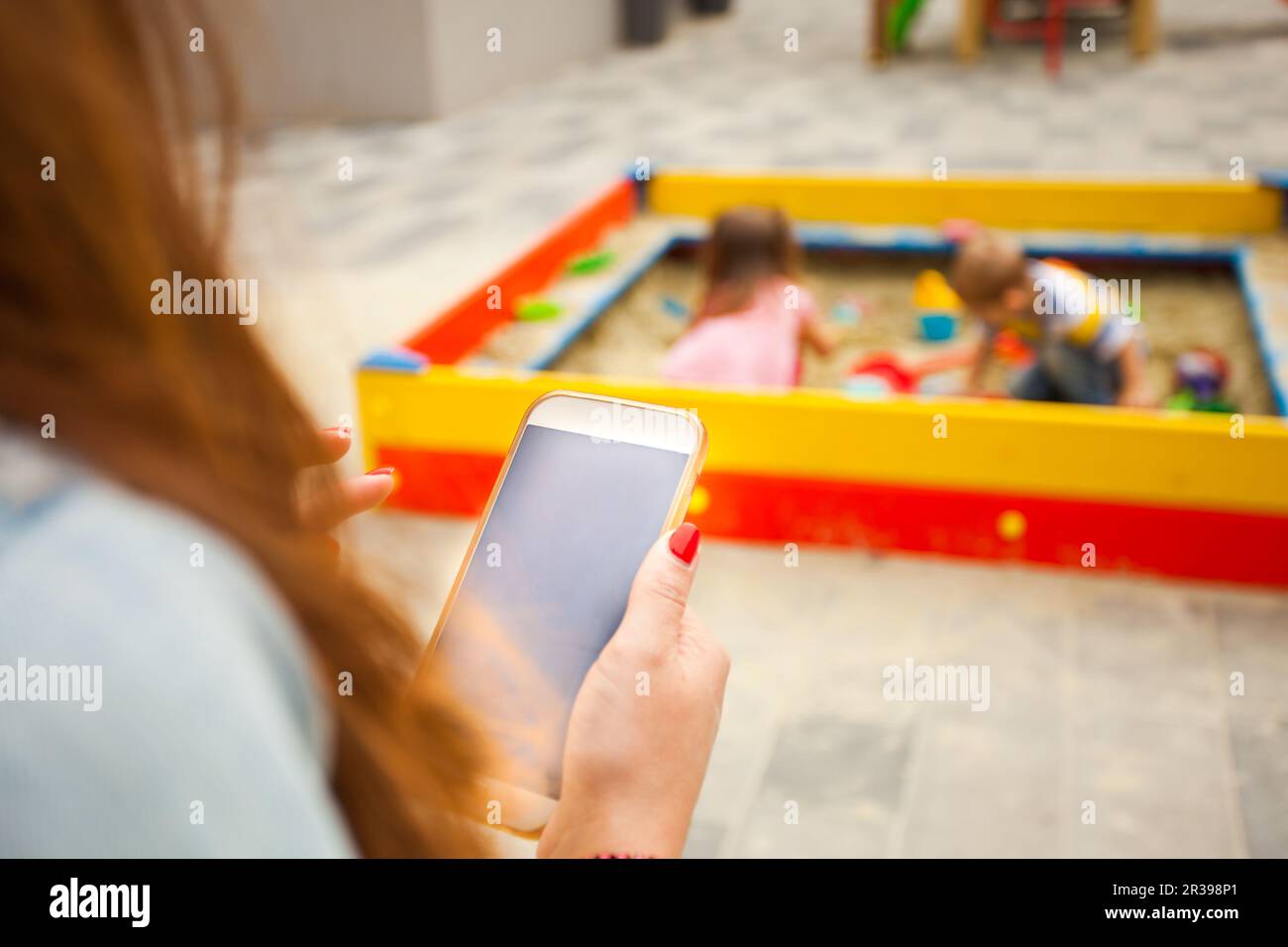 Mother sitting and looking at the screen of smartphone Stock Photo - Alamy