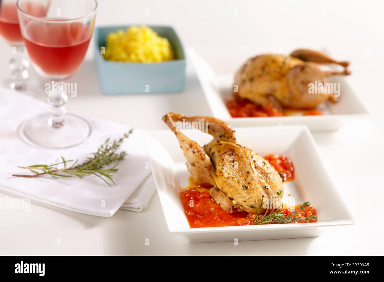 Fried quail on tomato sauce with saffron risotto Stock Photo - Alamy