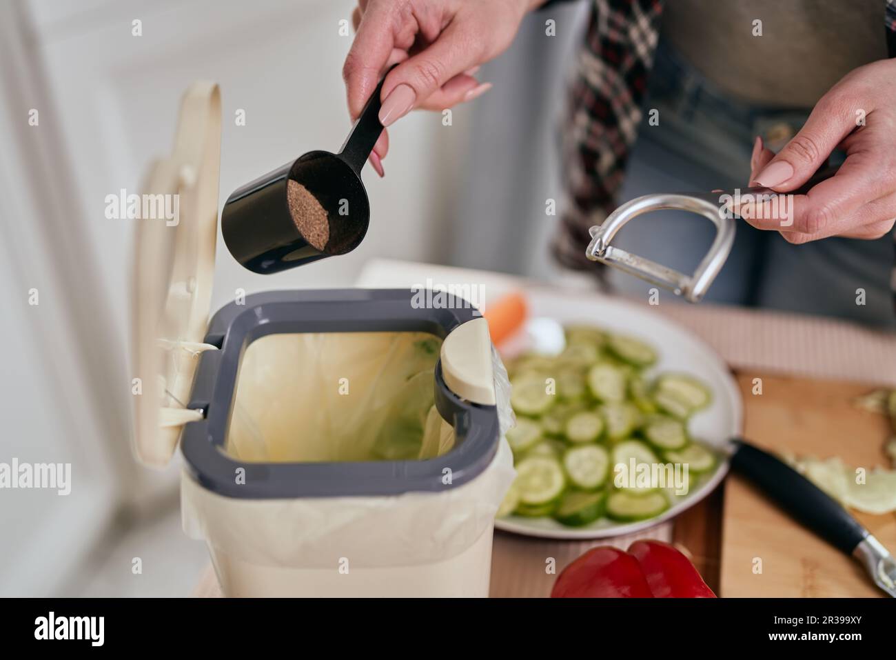 Woman put bokashi bran in a compost bin for fermentation. Responsible ...