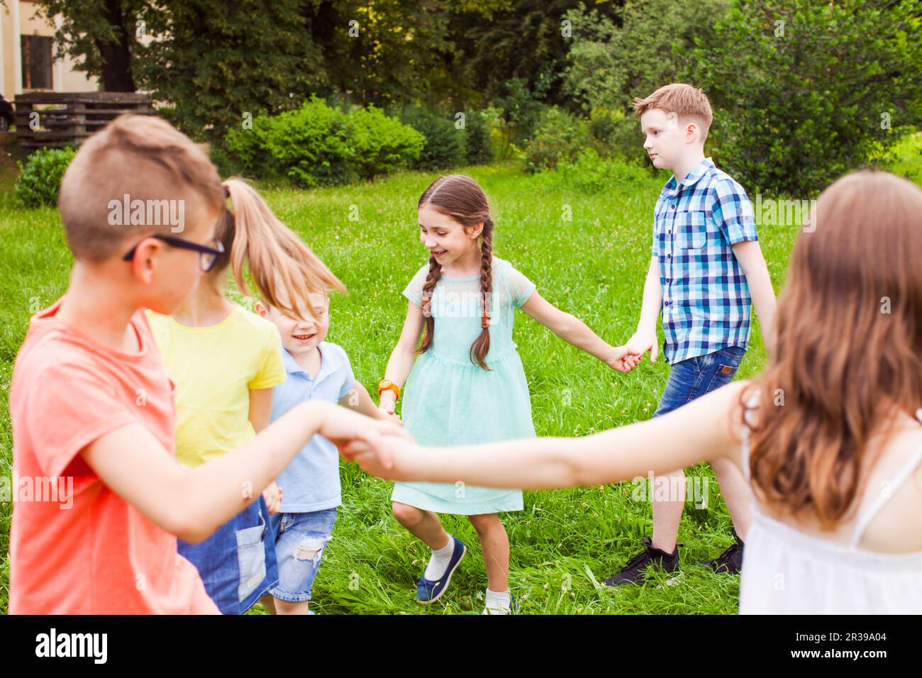 Happy children doing circle dance on the lawn in the park Stock Photo ...