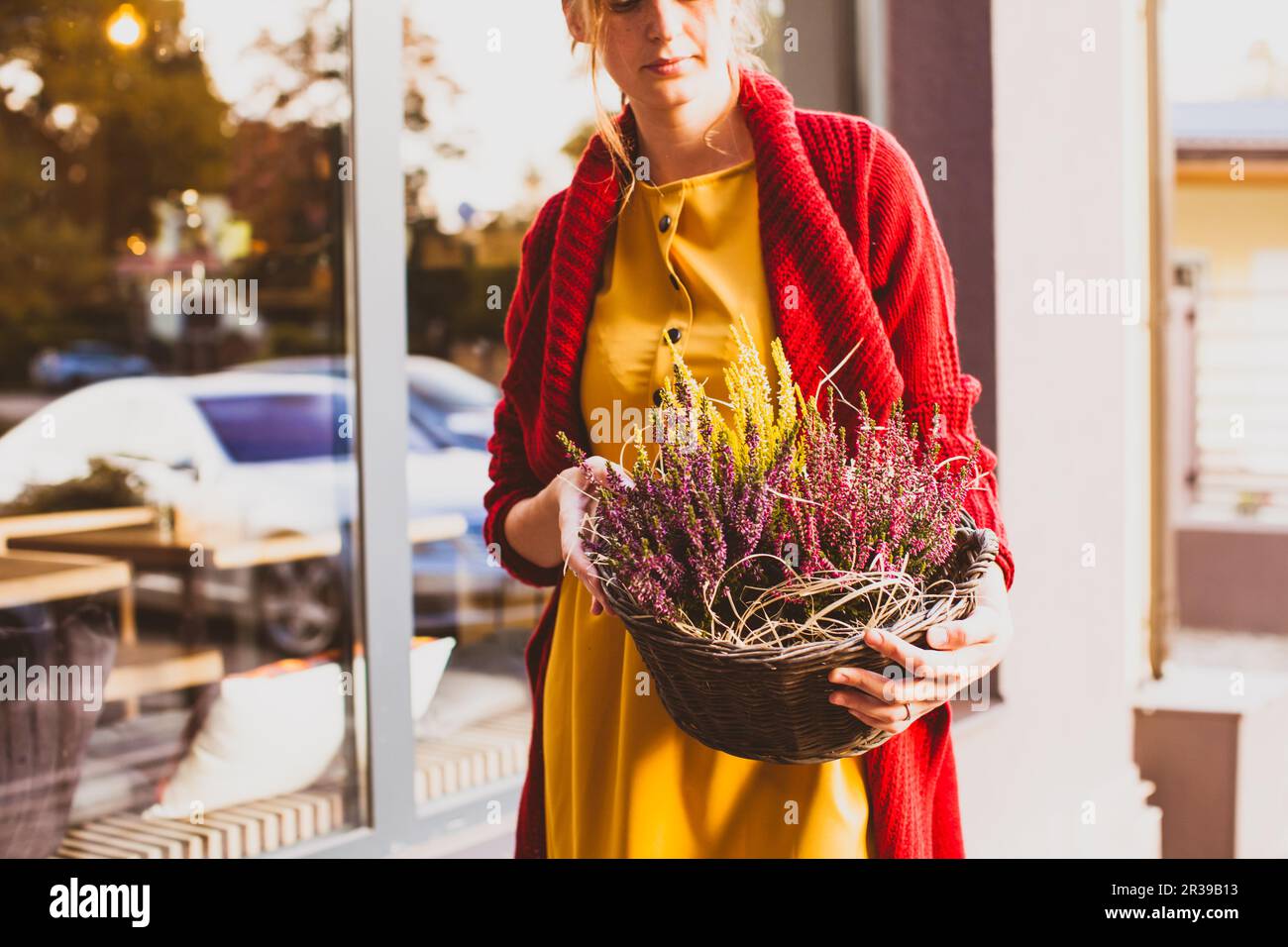 Young florist girl holding heather flowers in wicker basket Stock Photo ...