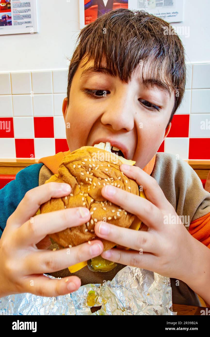 A boy eating a cheeseburger at a Five Guys Fast Food restaurant Stock ...