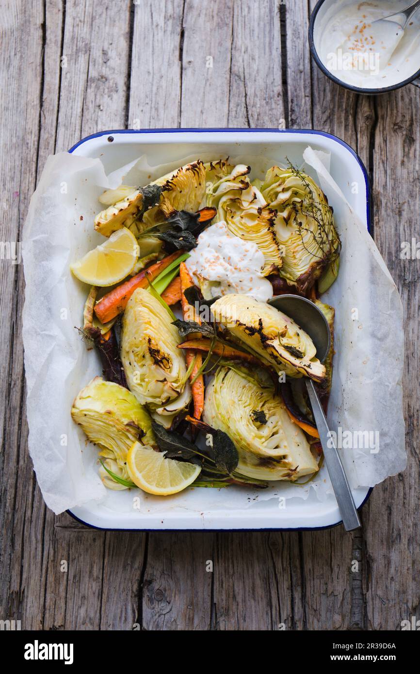 Roasted white cabbage in a baking dish with sage, carrots, lemon and a ...