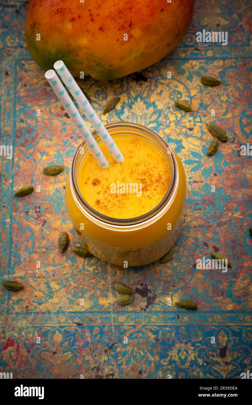 A mango lassi in a jar with a straw Stock Photo - Alamy